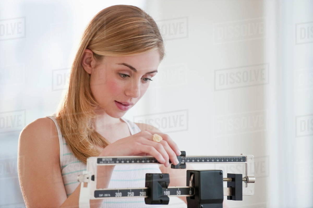 Young woman using measuring scales - Stock Photo - Dissolve