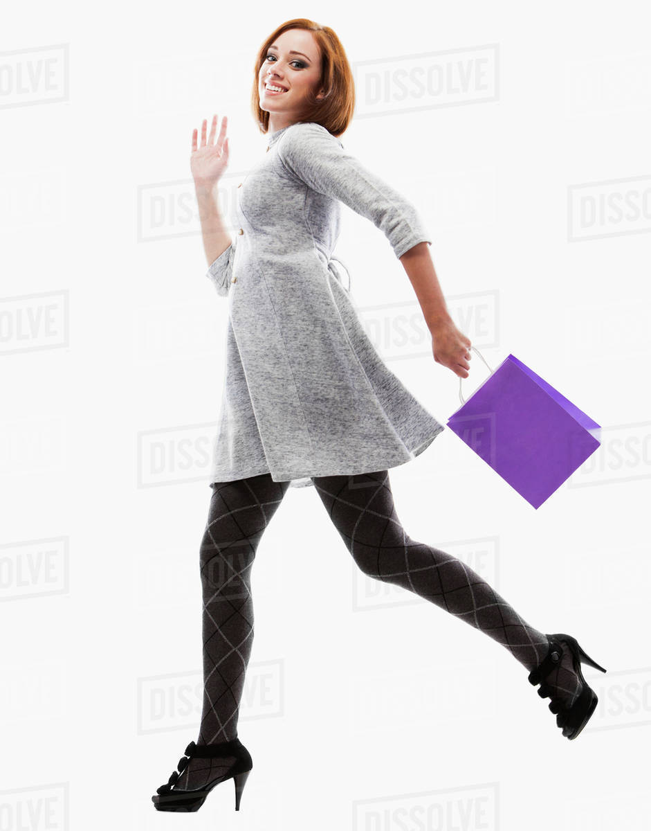 Young woman running with shopping bag, studio shot - Stock Photo - Dissolve