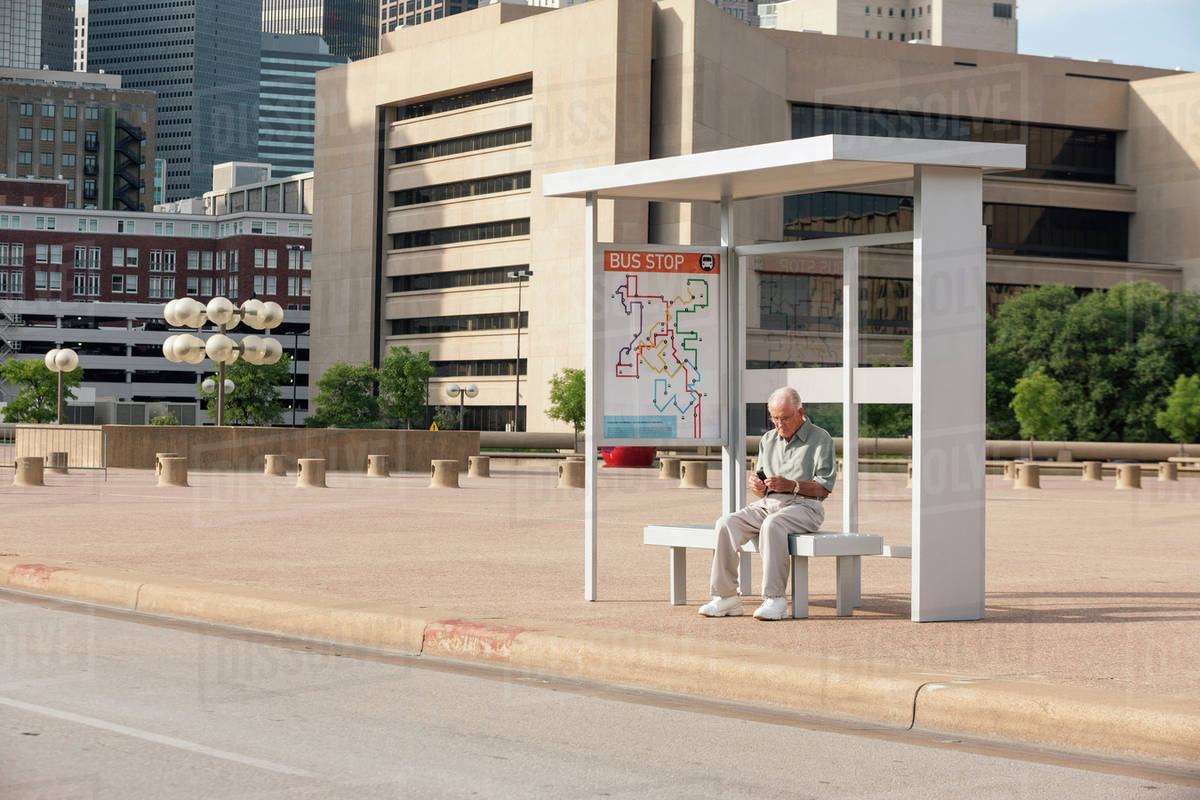 Senior man sitting at bus stop and text messaging - Royalty-free Stock ...