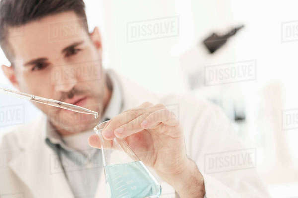 Man pouring liquid into conical flask - Royalty-free Stock Photo | Dissolve