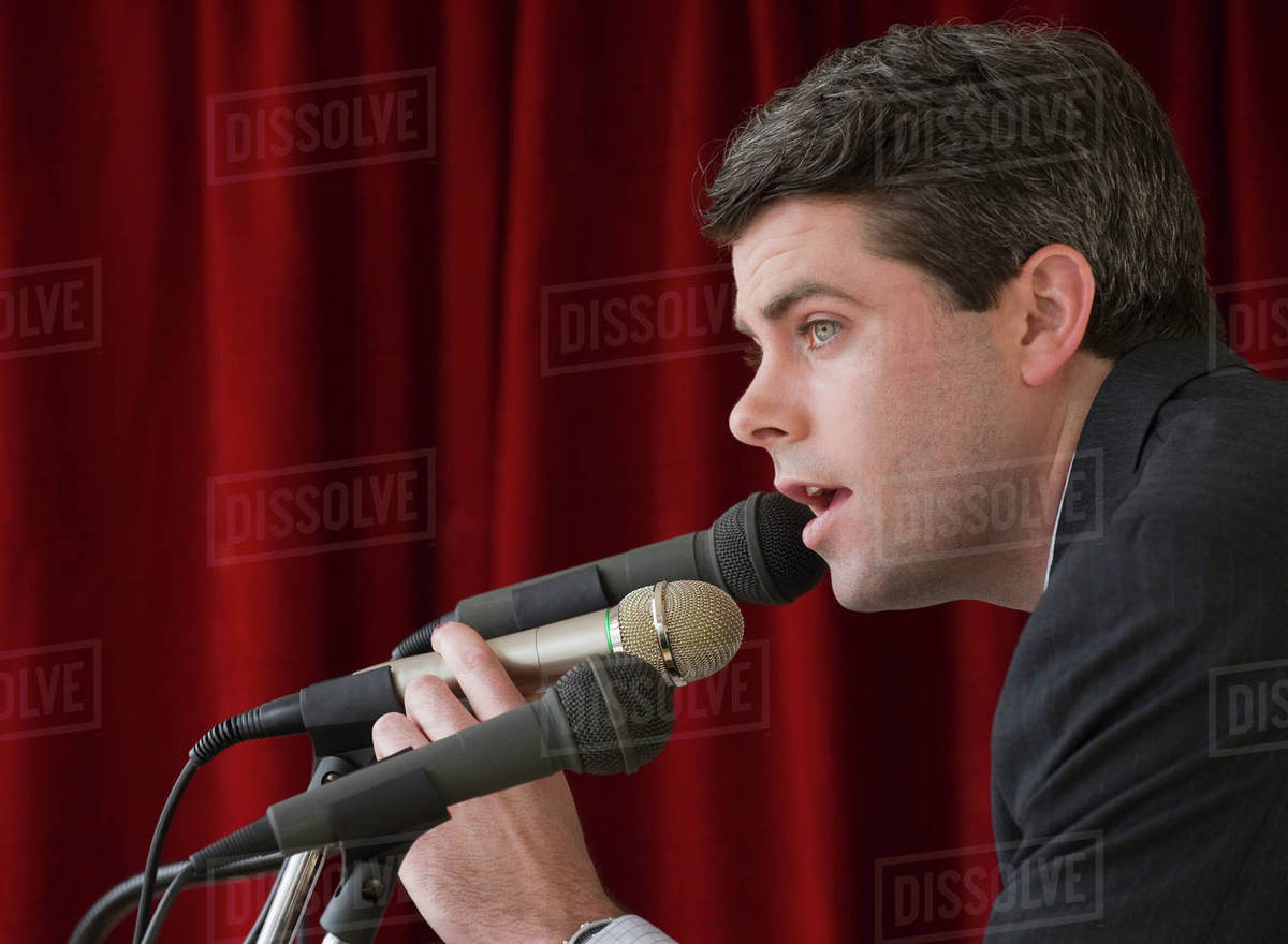 Businessman speaking into microphone - Stock Photo - Dissolve