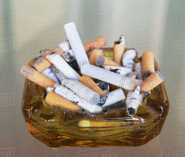 Ashtray filled with many cigarette butts - Stock Photo - Dissolve