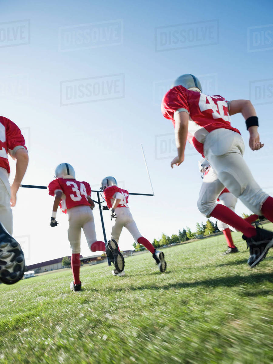 Football players running on field - Stock Photo - Dissolve
