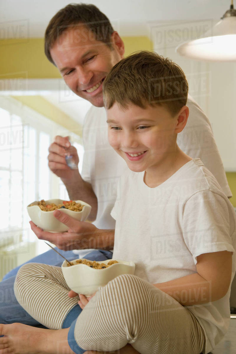 Father and son eating breakfast on kitchen counter - Stock Photo - Dissolve