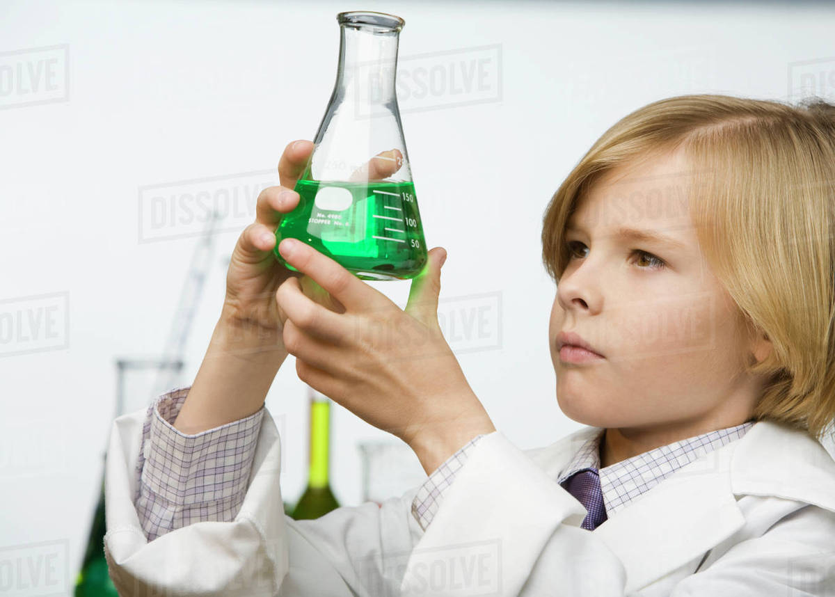 Boy looking at beaker of liquid - Royalty-free Stock Photo | Dissolve