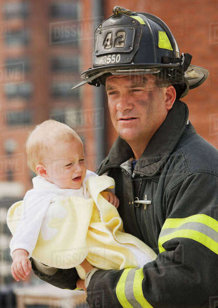 Male firefighter carrying baby - Royalty-free Stock Photo | Dissolve