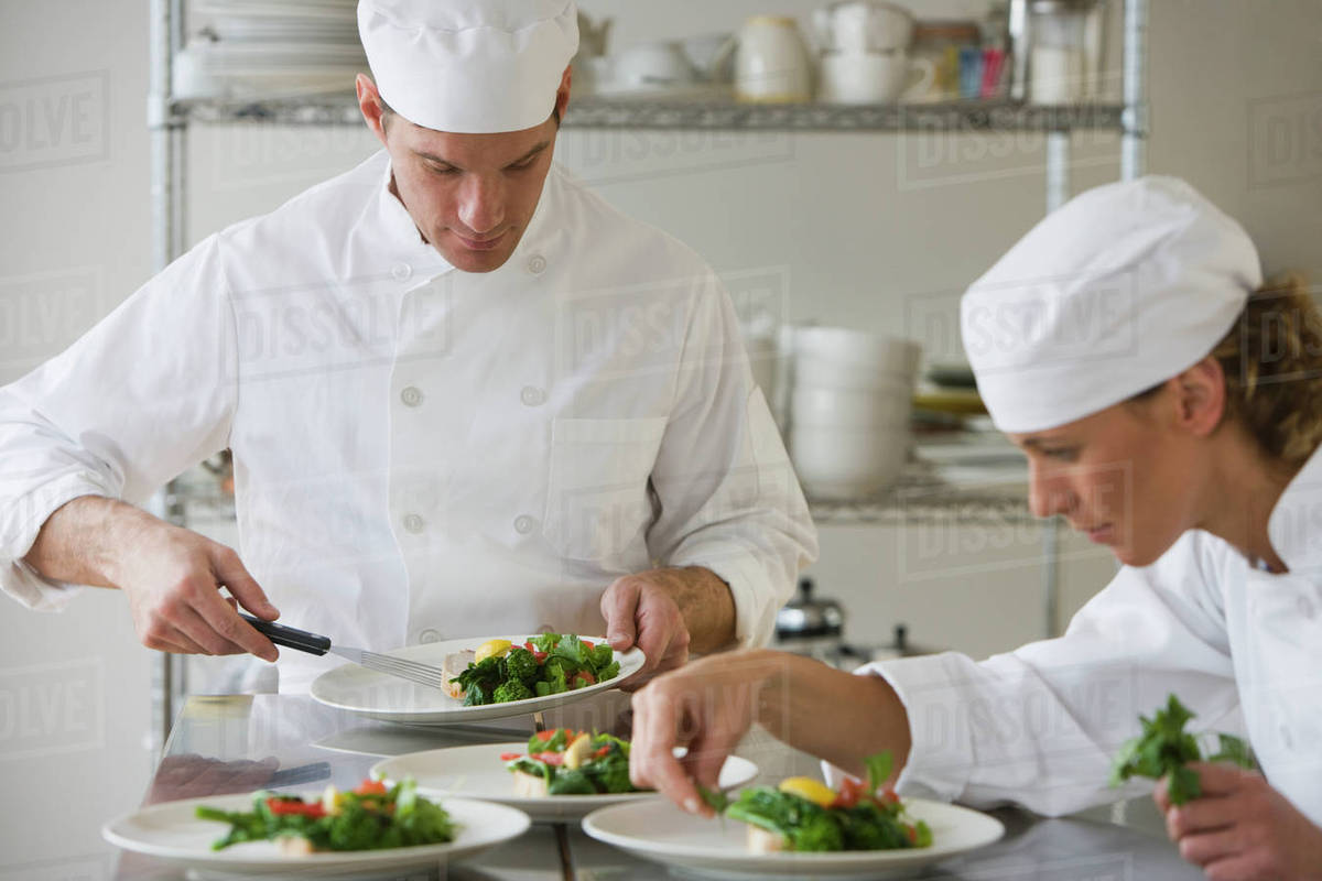 Male and female chefs plating food - Royalty-free Stock Photo | Dissolve
