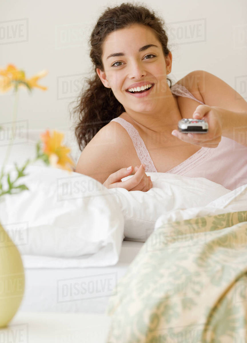 Woman pointing remote control - Stock Photo - Dissolve