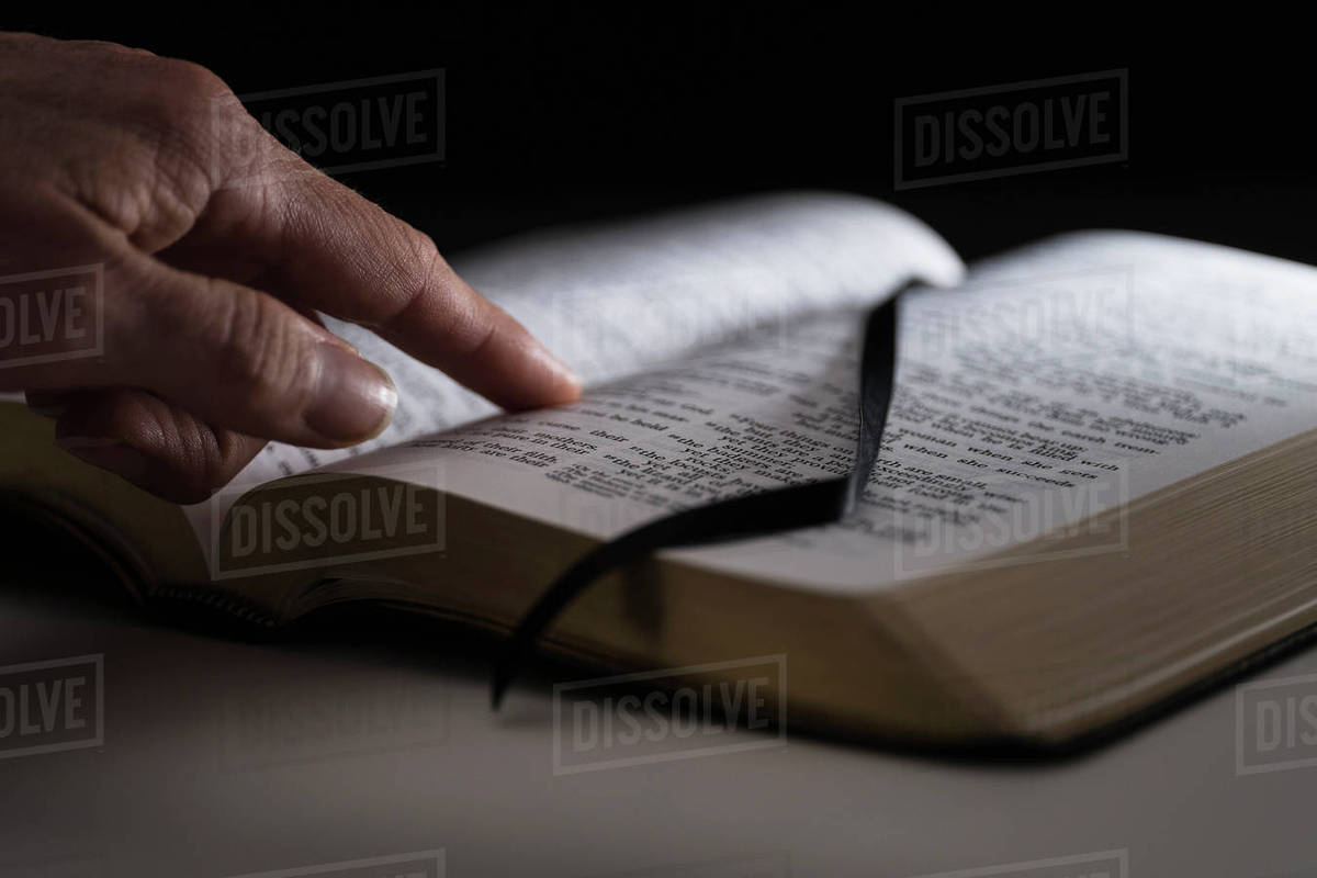 Human finger on open Bible - Stock Photo - Dissolve