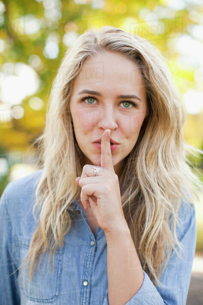 Front view portrait of young woman with finger on lips - Royalty-free ...