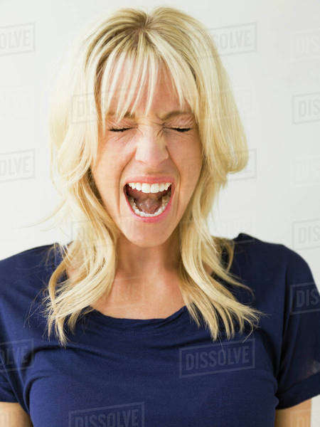 Studio portrait of blonde woman screaming - Stock Photo - Dissolve