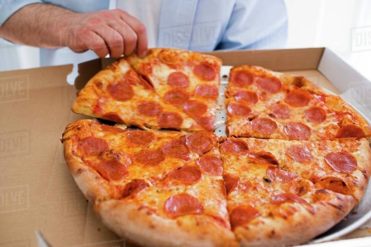 Hand taking piece of pepperoni pizza out of pizza box - Royalty-free ...