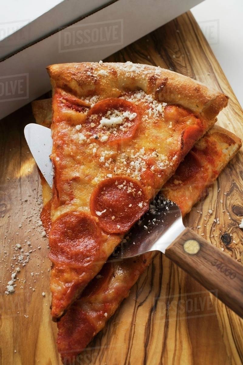 Two pieces of pepperoni pizza with server on wooden board - Royalty ...
