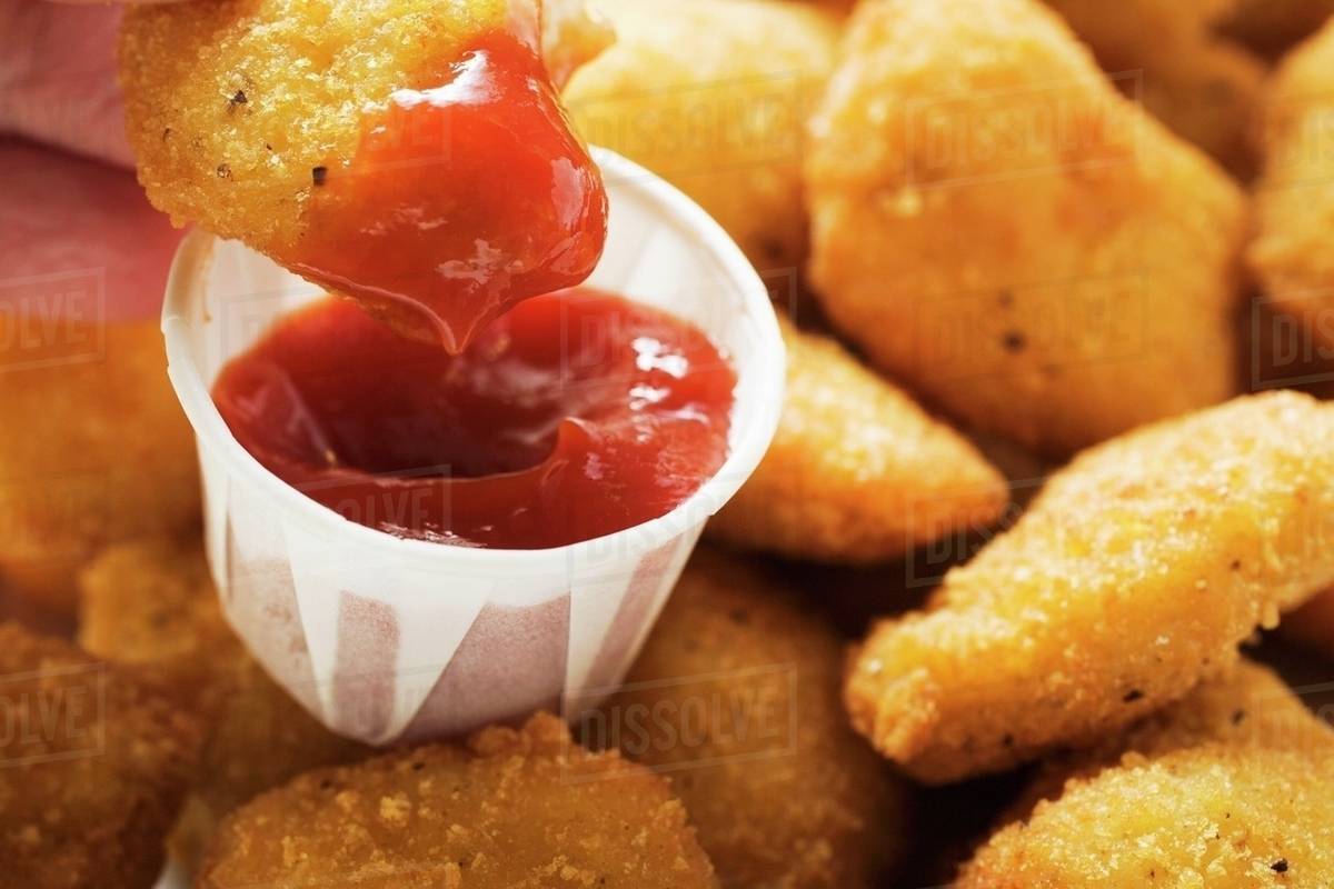 Dipping a chicken nugget in ketchup - Royalty-free Stock Photo | Dissolve