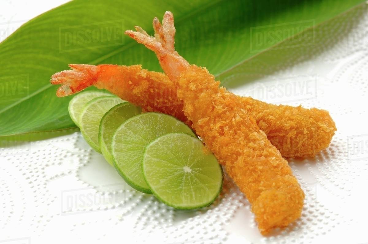 Breaded, deep-fried prawns with slices of lime - Stock Photo - Dissolve