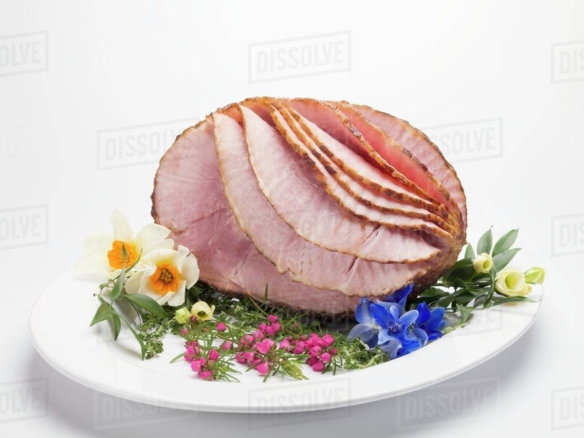 Roast ham, partly carved, on platter with edible flowers - Royalty-free ...