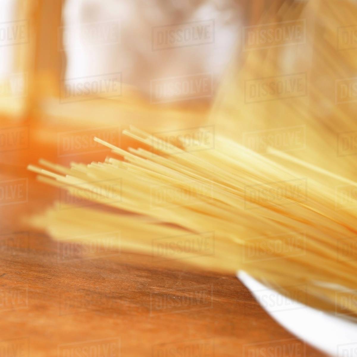 Uncooked spaghetti falling into a deep plate - Royalty-free Stock Photo ...