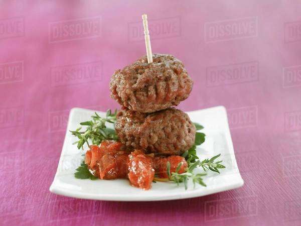 Two meatballs on tomato with herbs - Stock Photo - Dissolve