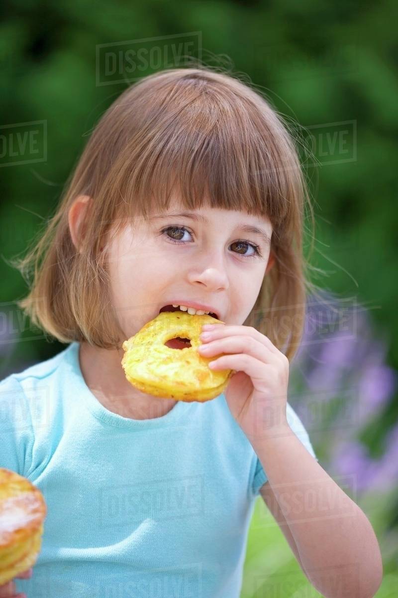 Girl eating an apple fritter - Stock Photo - Dissolve
