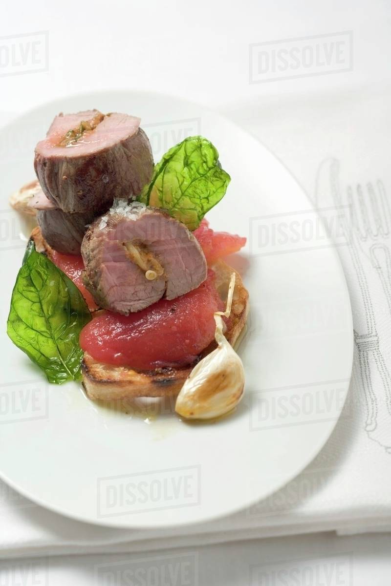 Pork fillet, tomatoes & deep-fried basil on toast - Stock Photo - Dissolve