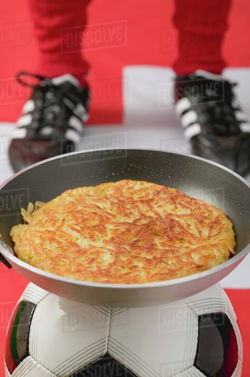 Rosti in frying pan on football, footballer in background - Royalty ...