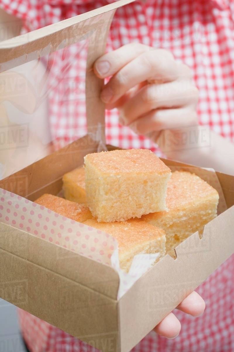 Woman holding box of cornbread (pieces) - Stock Photo - Dissolve