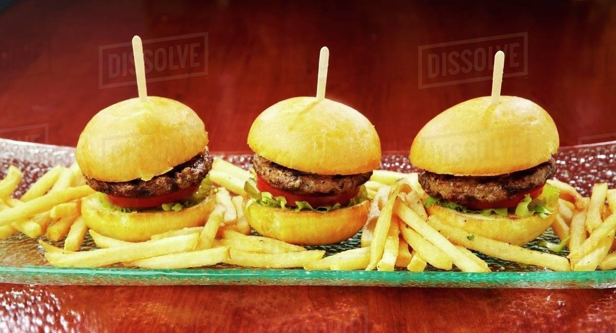 Three mini burgers with chips on a long serving platter - Stock Photo ...