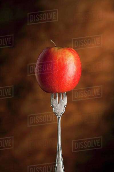 A red apple skewered on a fork - Royalty-free Stock Photo | Dissolve