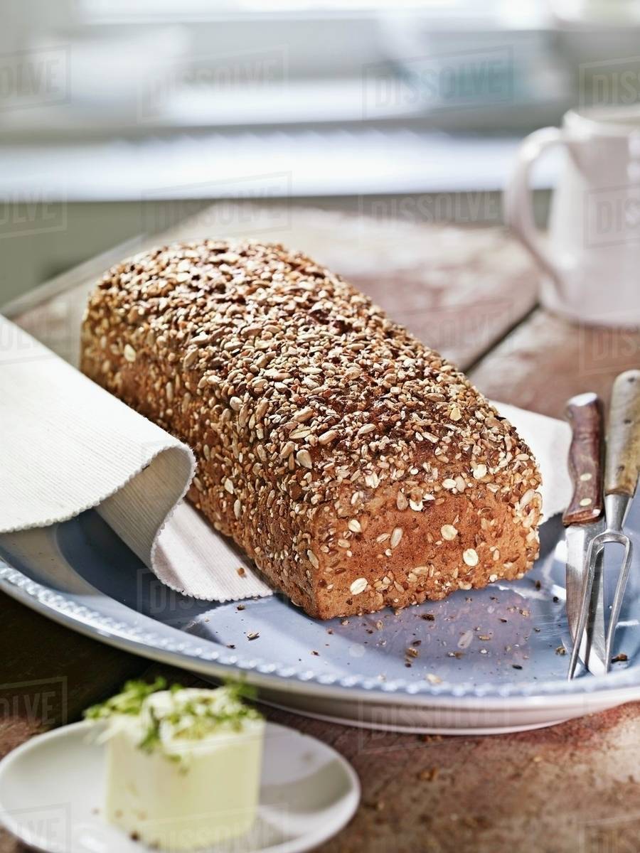 A whole loaf of wholemeal rye bread with seeds on a plate - Royalty ...
