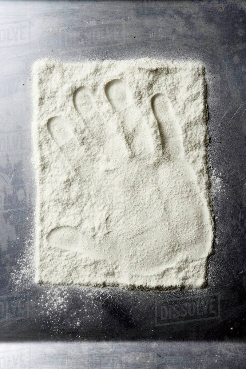 A hand print in flour (seen from above) - Stock Photo - Dissolve