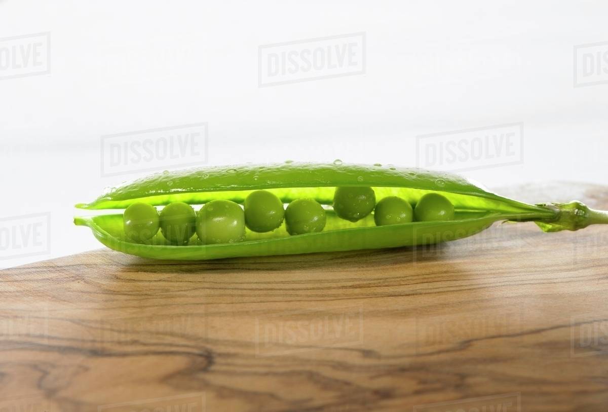 Open pea pod on a wooden board - Royalty-free Stock Photo | Dissolve