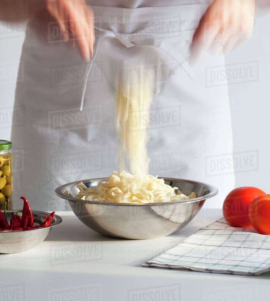 A woman mixing pasta in a bowl - Stock Photo - Dissolve