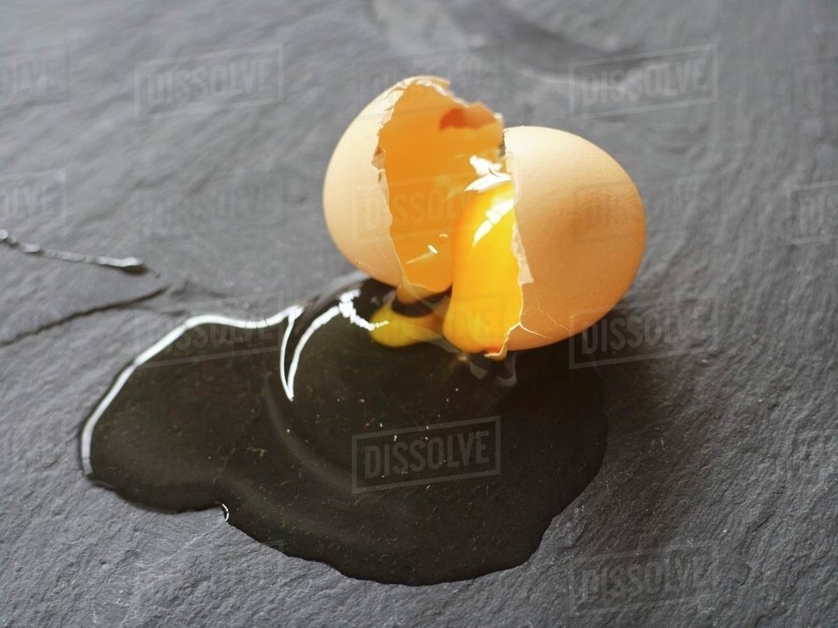 A cracked-open egg on a slate slab - Royalty-free Stock Photo | Dissolve