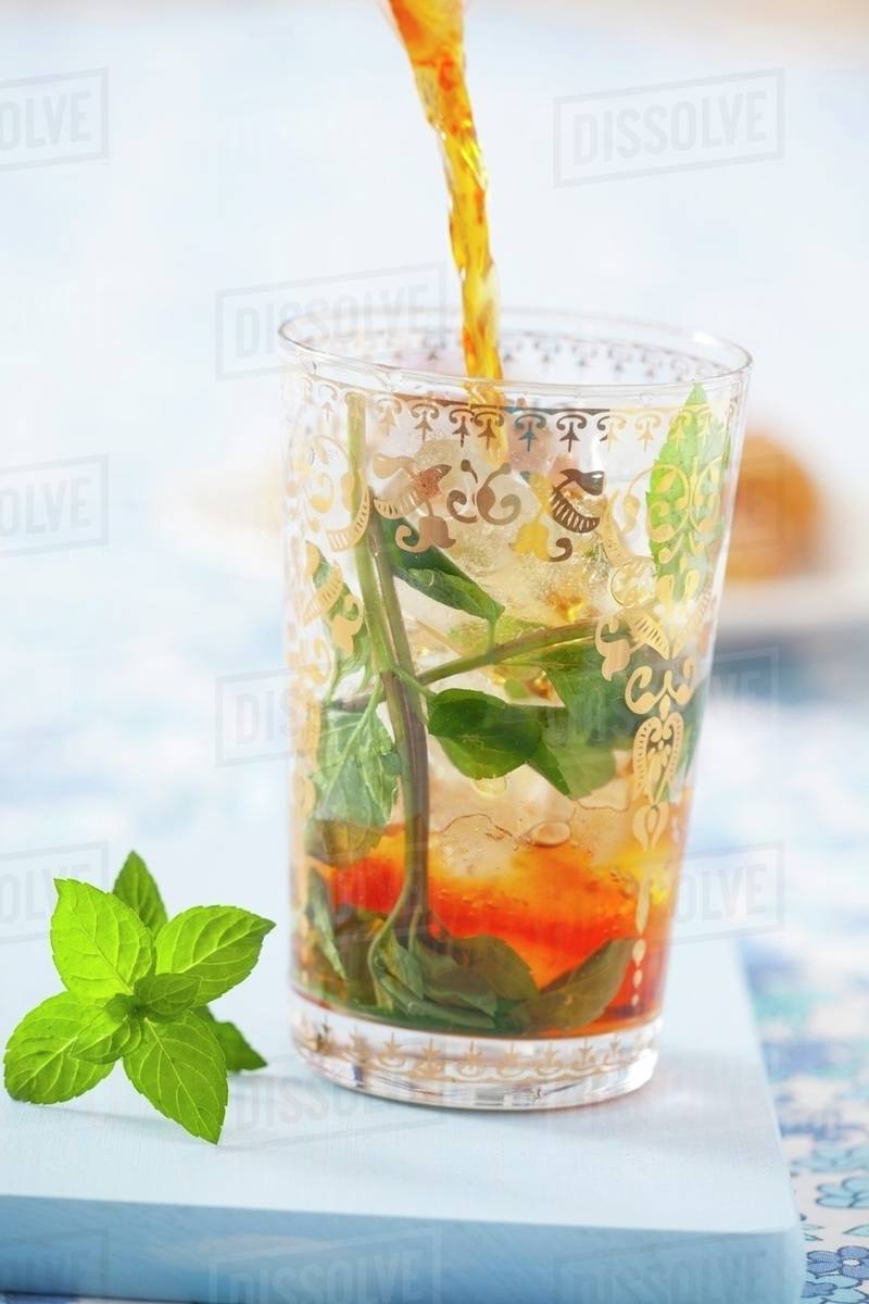 Iced tea being poured into a glass with ice cubes and mint - Royalty ...