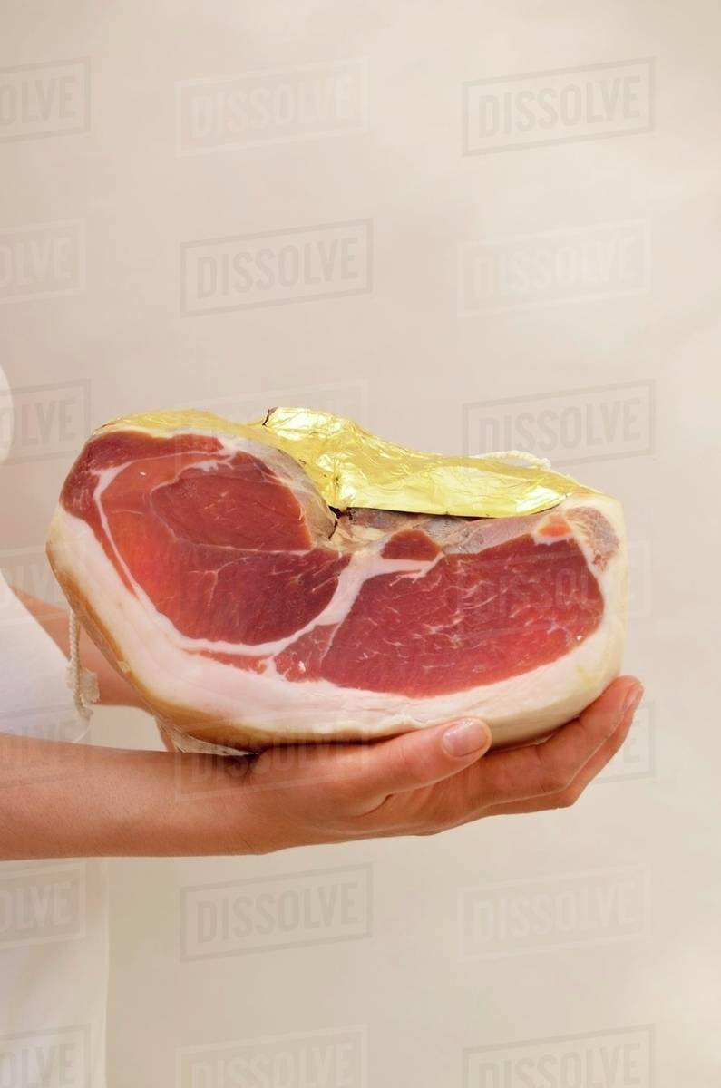 A woman holding a Parma ham wrapped in gold foil - Royalty-free Stock ...