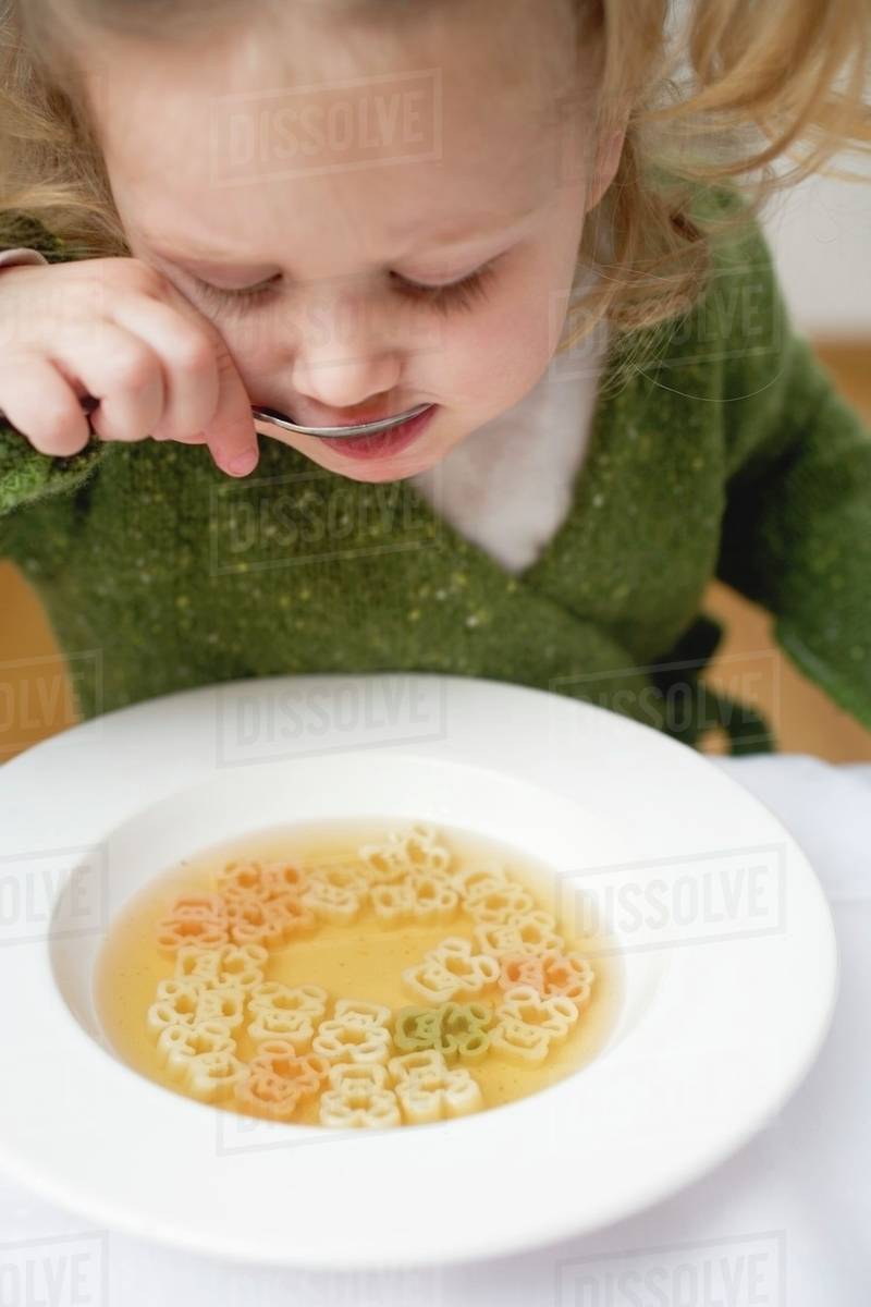Small girl eating soup with teddy bear pasta - Royalty-free Stock Photo ...