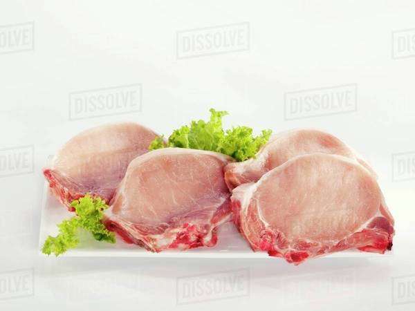 Four pork chops on a serving platter - Stock Photo - Dissolve