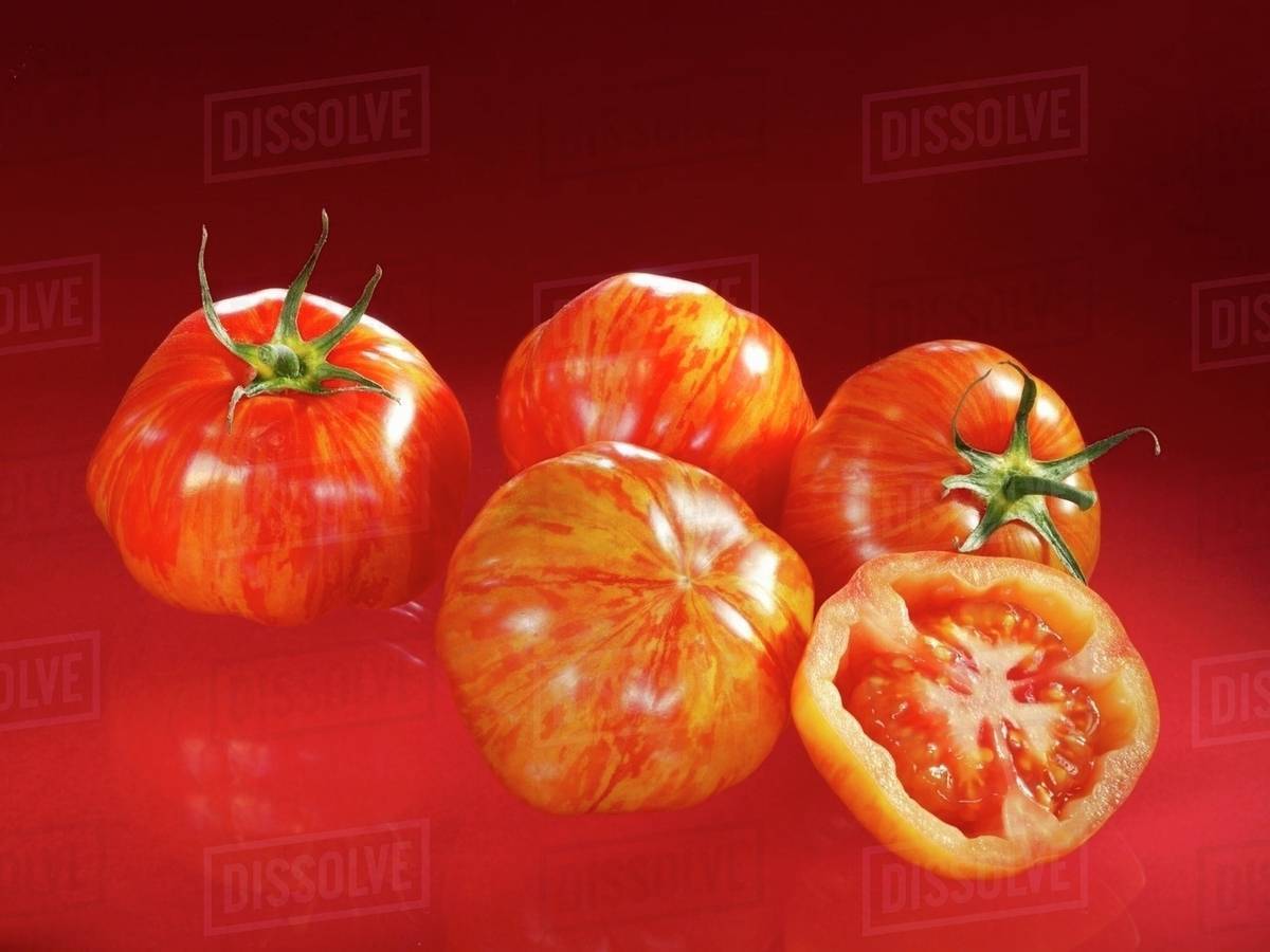 Tiger tomatoes, four whole and one half - Stock Photo - Dissolve