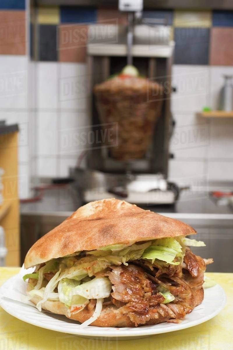 A doner kebab with meat on spit in background - Stock Photo - Dissolve