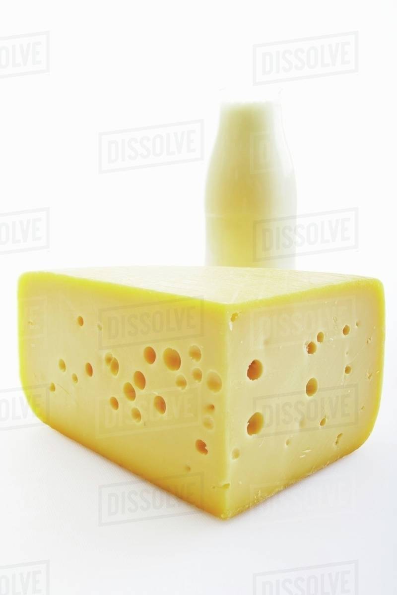 A piece of cheese with a bottle of milk in the background - Stock Photo ...