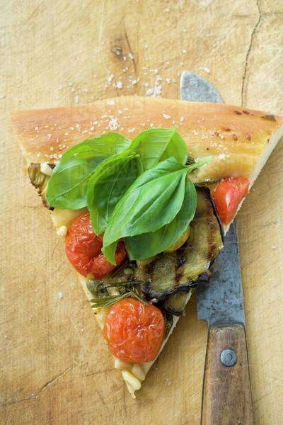 Slice of pizza with tomatoes, aubergines and basil - Stock Photo - Dissolve