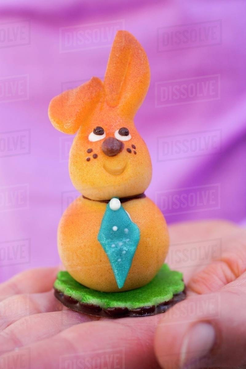 Hand holding marzipan Easter Bunny - Stock Photo - Dissolve