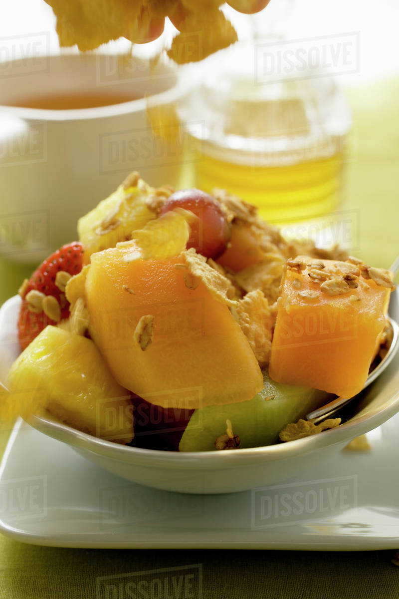 Sprinkling muesli flakes over a fruit salad - Royalty-free Stock Photo ...