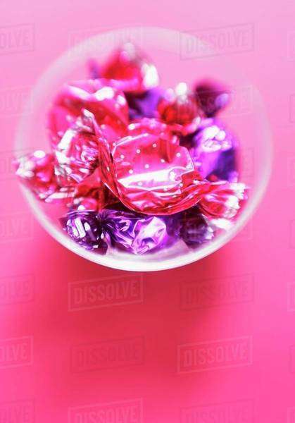 Sweets in pink and purple wrappers in a small bowl - Royalty-free Stock ...