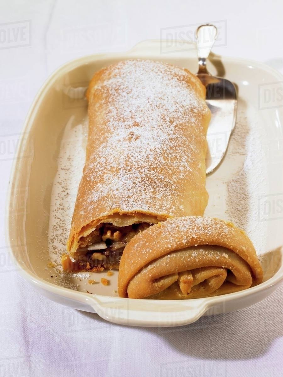 Fruit strudel with nuts and icing sugar, partly sliced - Royalty-free ...