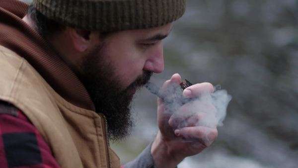 Lumberjack smoking a pipe by the river - Stock Video Footage - Dissolve