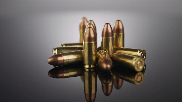 Gun Control. Ammunition of 9mm bullets rotating on a reflective surface ...