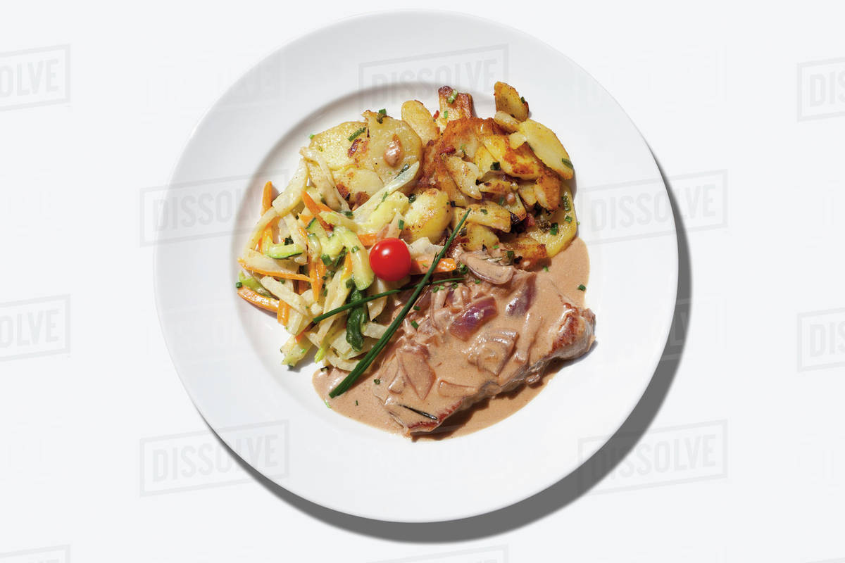 Saddle of pork steak with chipped potatoes and julienne vegegetables on ...