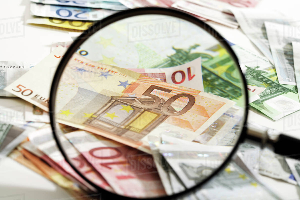 Euro banknotes under magnifying glass, close-up - Stock Photo - Dissolve