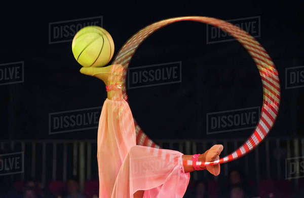Juggler in the circus juggling with ball and hoop - Stock Photo - Dissolve